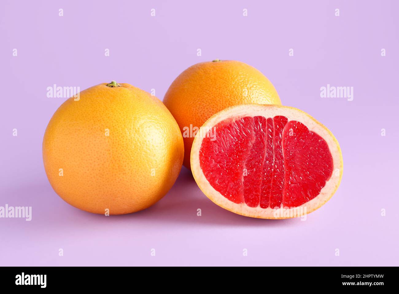 Tasty ripe grapefruits on purple background Stock Photo - Alamy