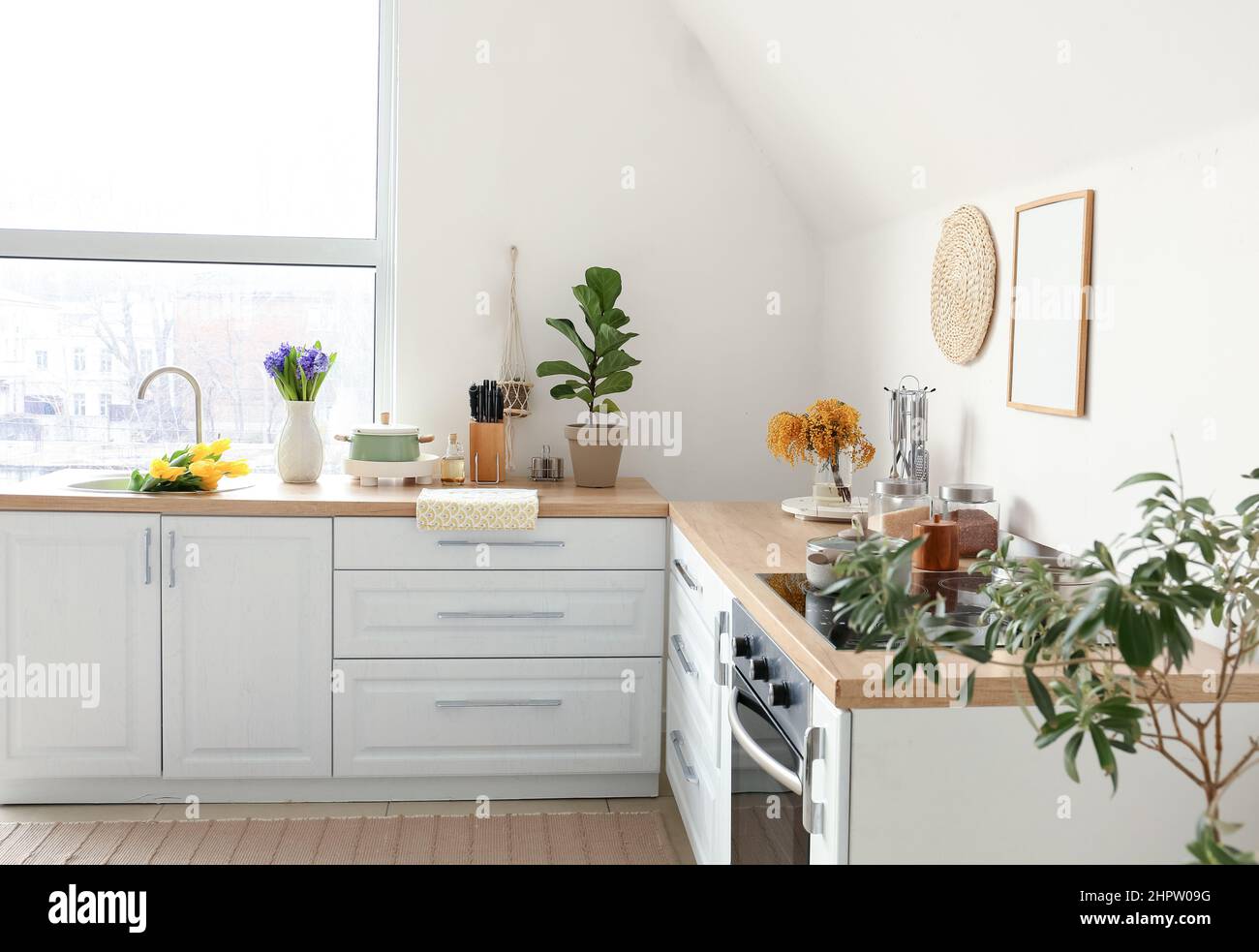 Kitchen counters with beautiful flowers and utensils near white wall ...