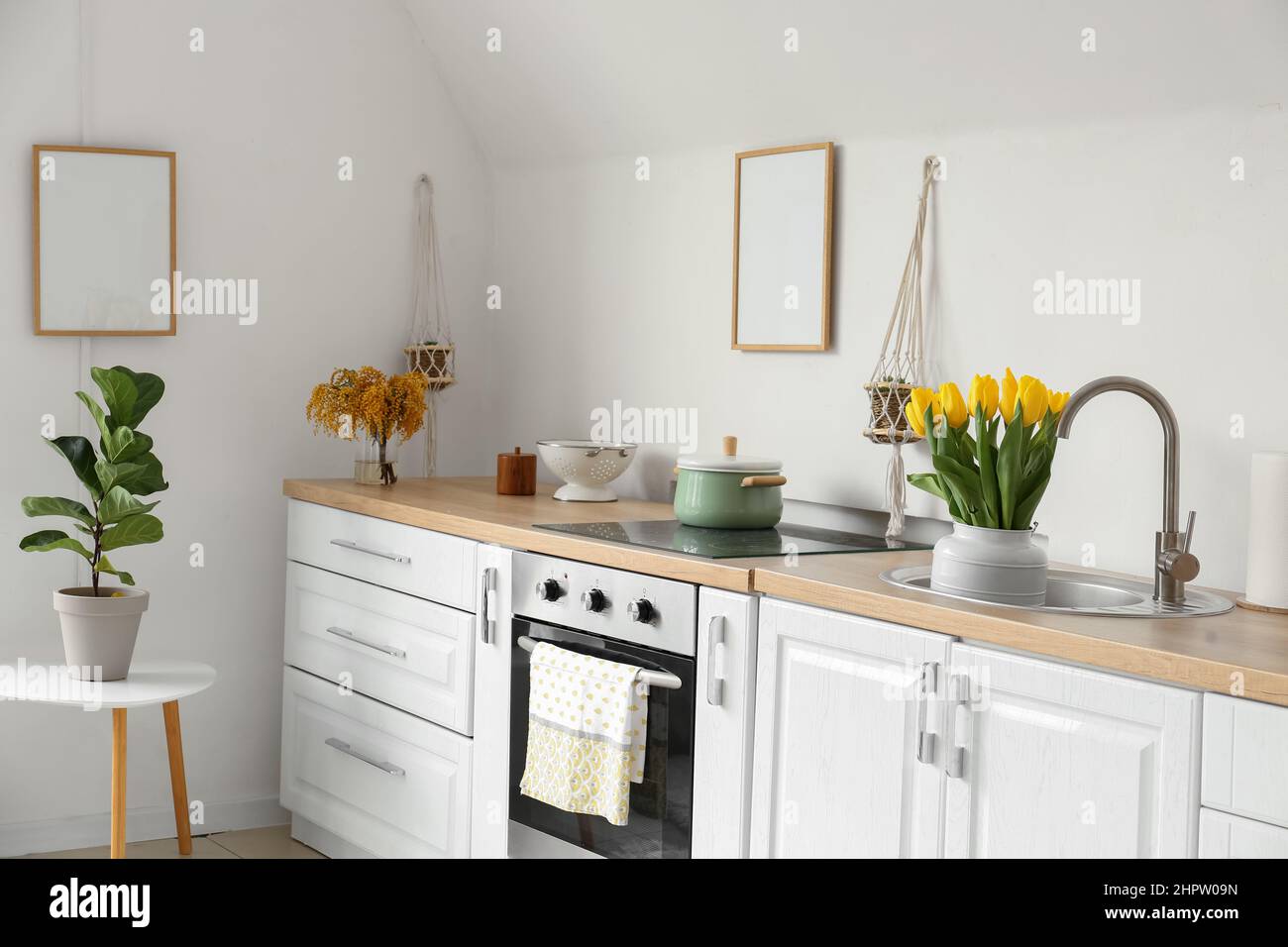 Tulips in sink and utensils on kitchen counters near white wall Stock ...