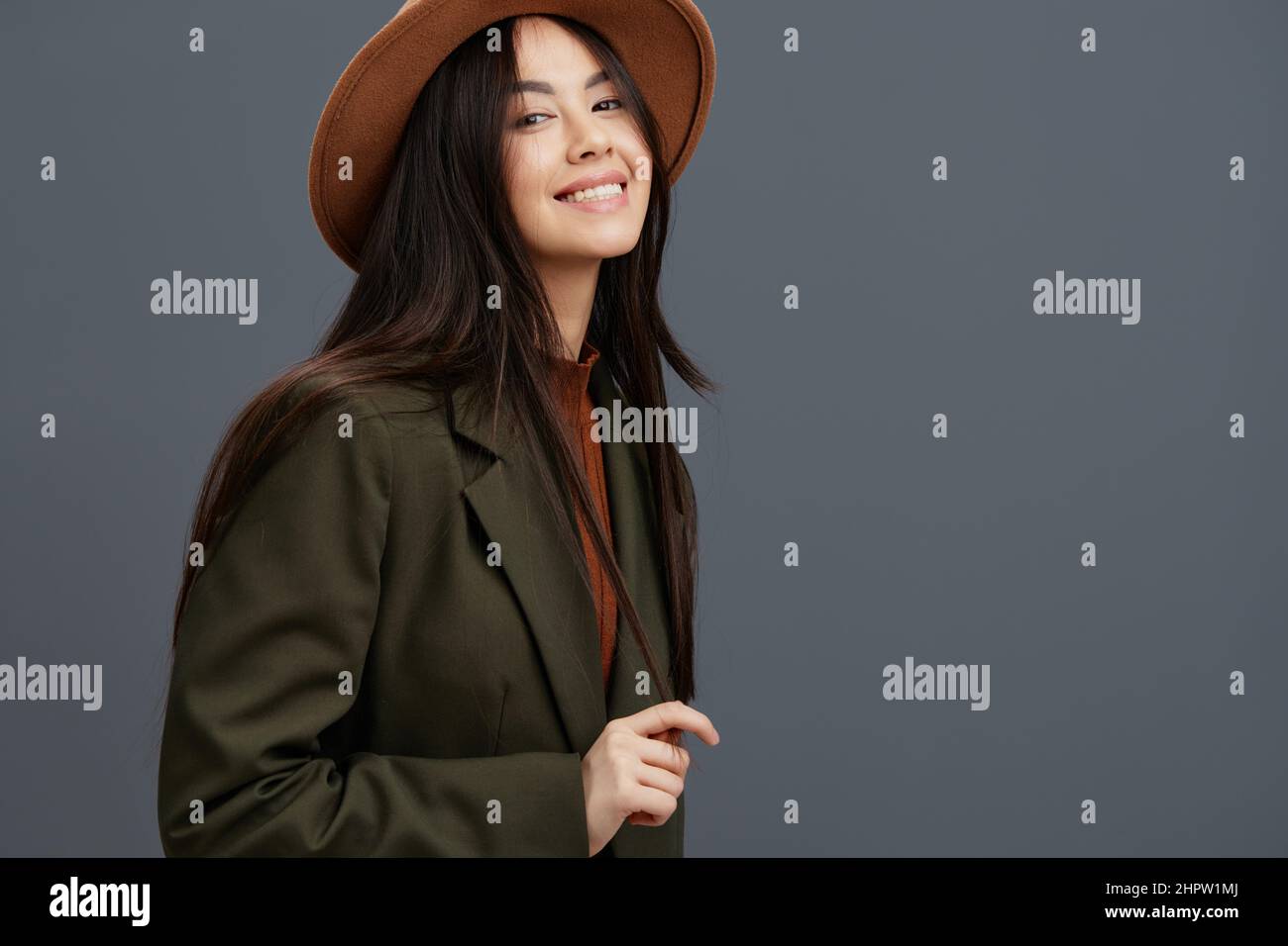 pretty woman in a suit with a hat posing casual wear Gray background ...