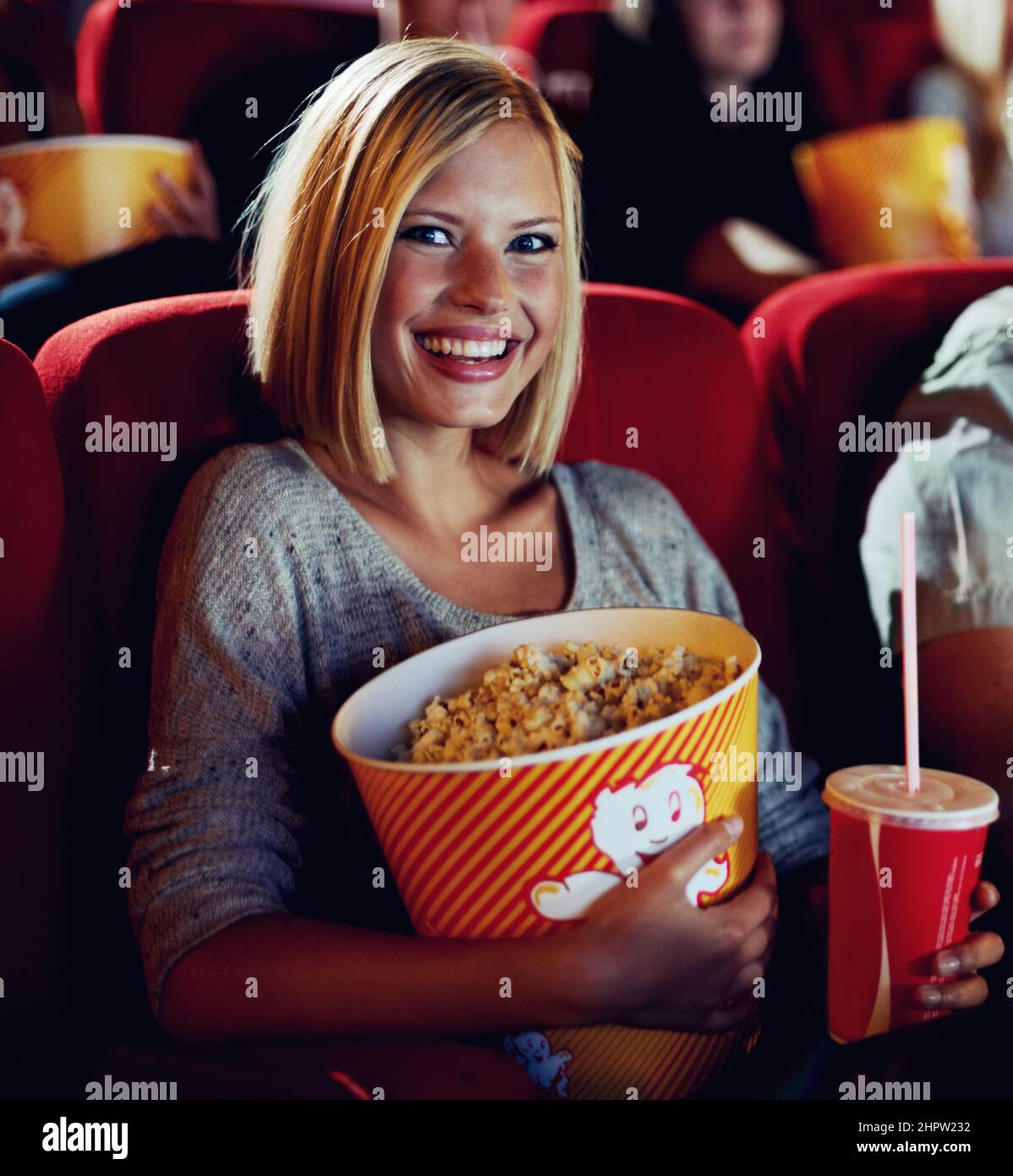 Movie magic. A portrait of a happy young girl holdng a tub of popcorn ...