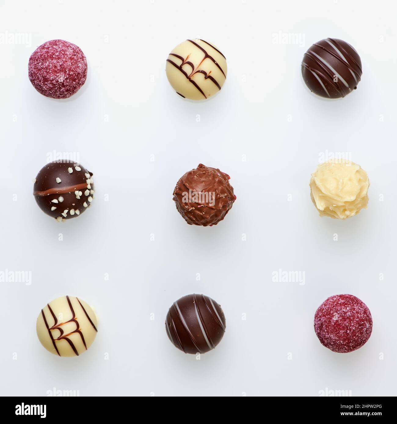 nine chocolate truffles in three symmetrical rows on a white background ...