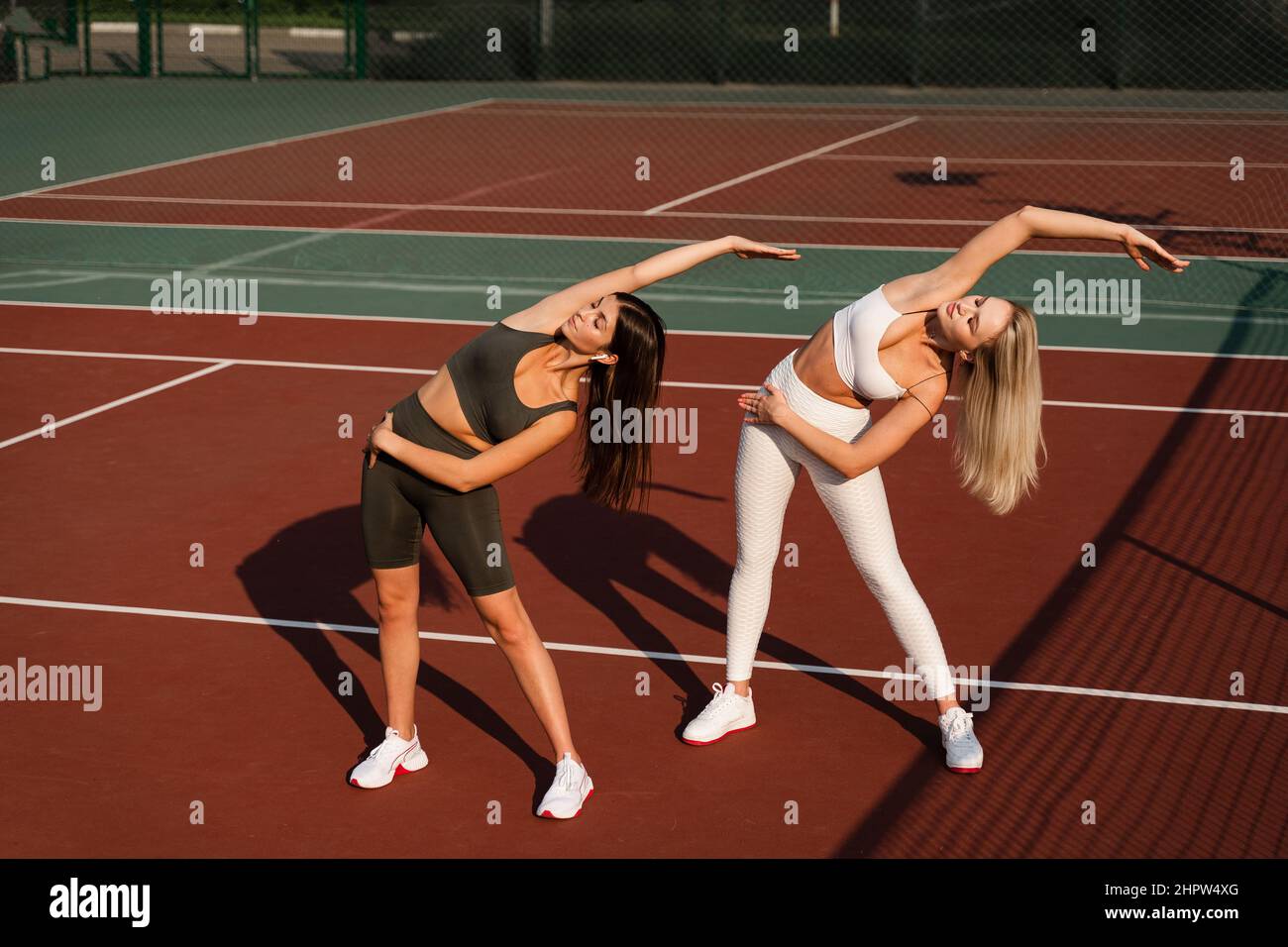 2 girls doing stretching before sports training. Outside group training ...