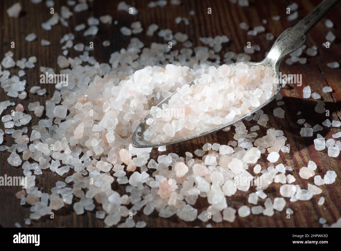 A pile of salt in metal spoon on dark background. Spices. Excessive ...