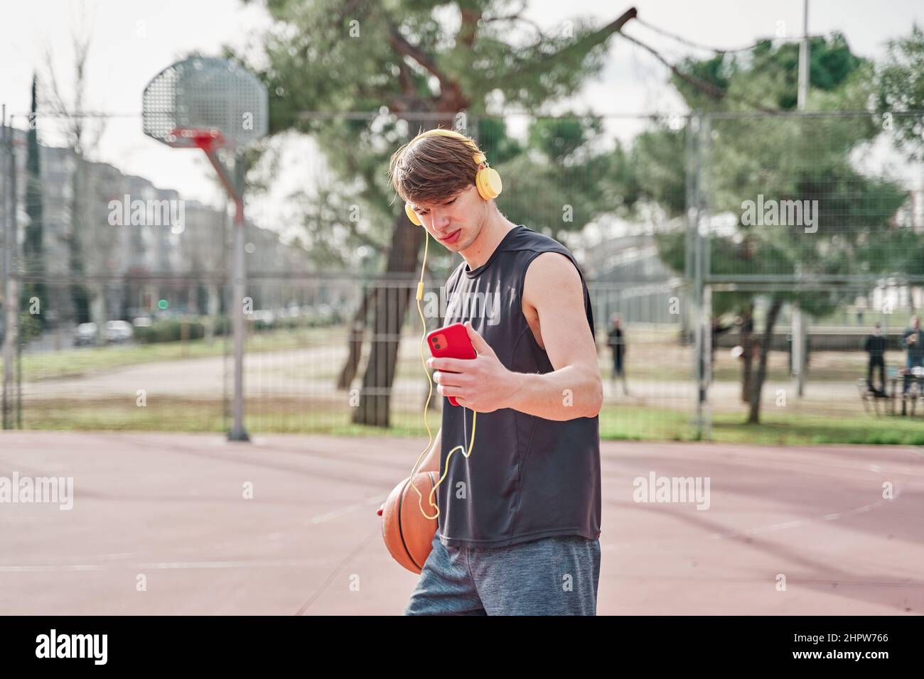 young athlete on a basketball court training while listening to music ...