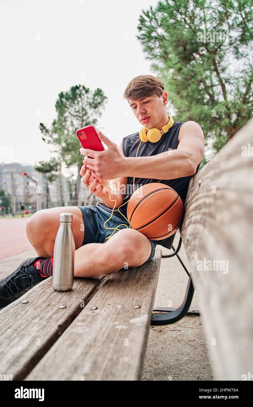 basketball player resting. male athlete sitting while making a video ...