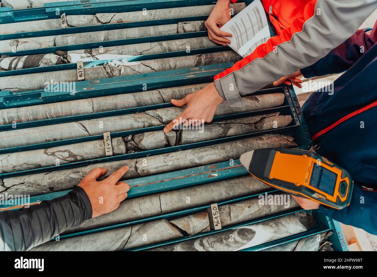 Geological gold core samples with team of mining workers measuring ...