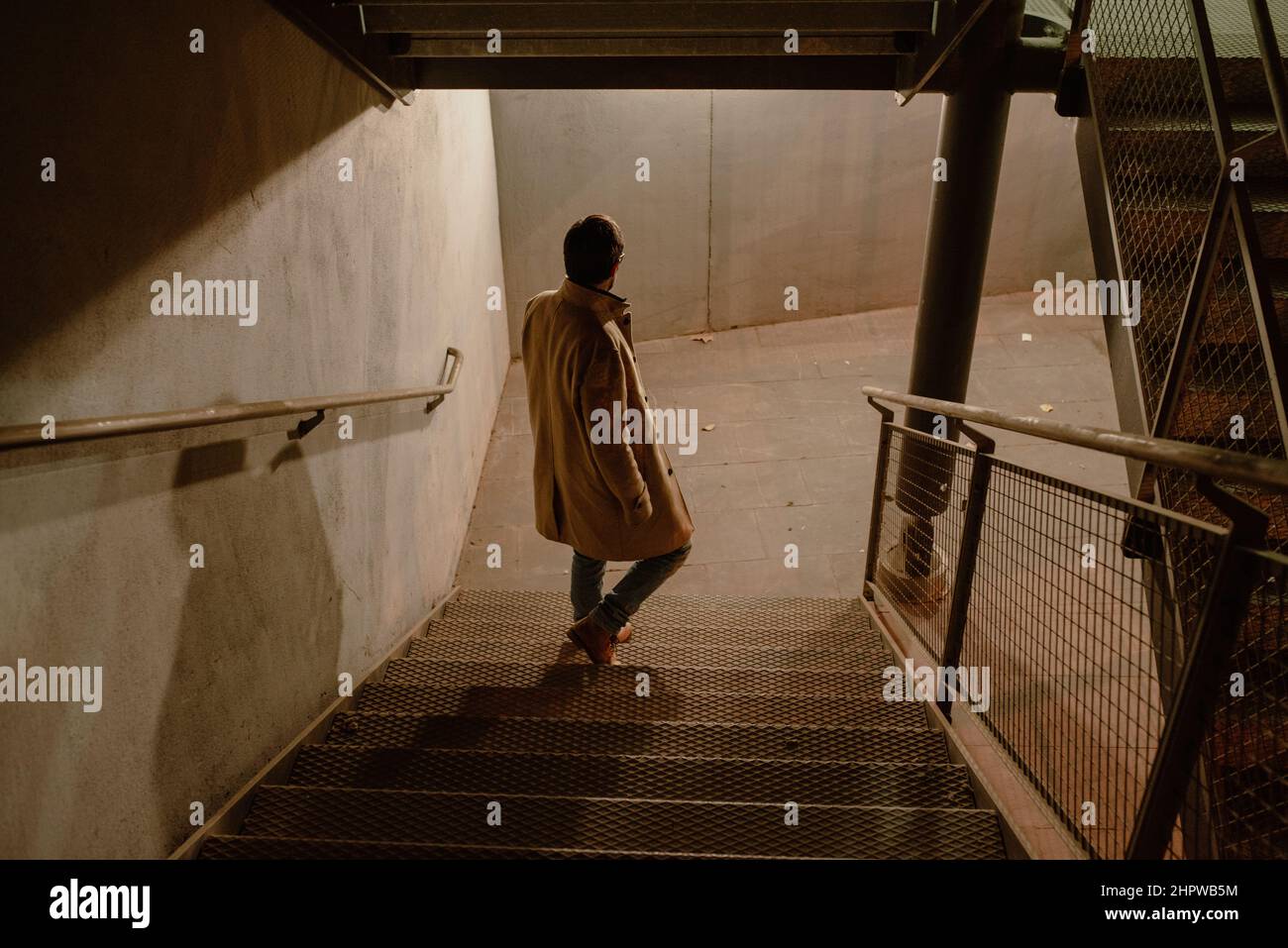 Man descending metal emergency stairs in the shadows of the night ...