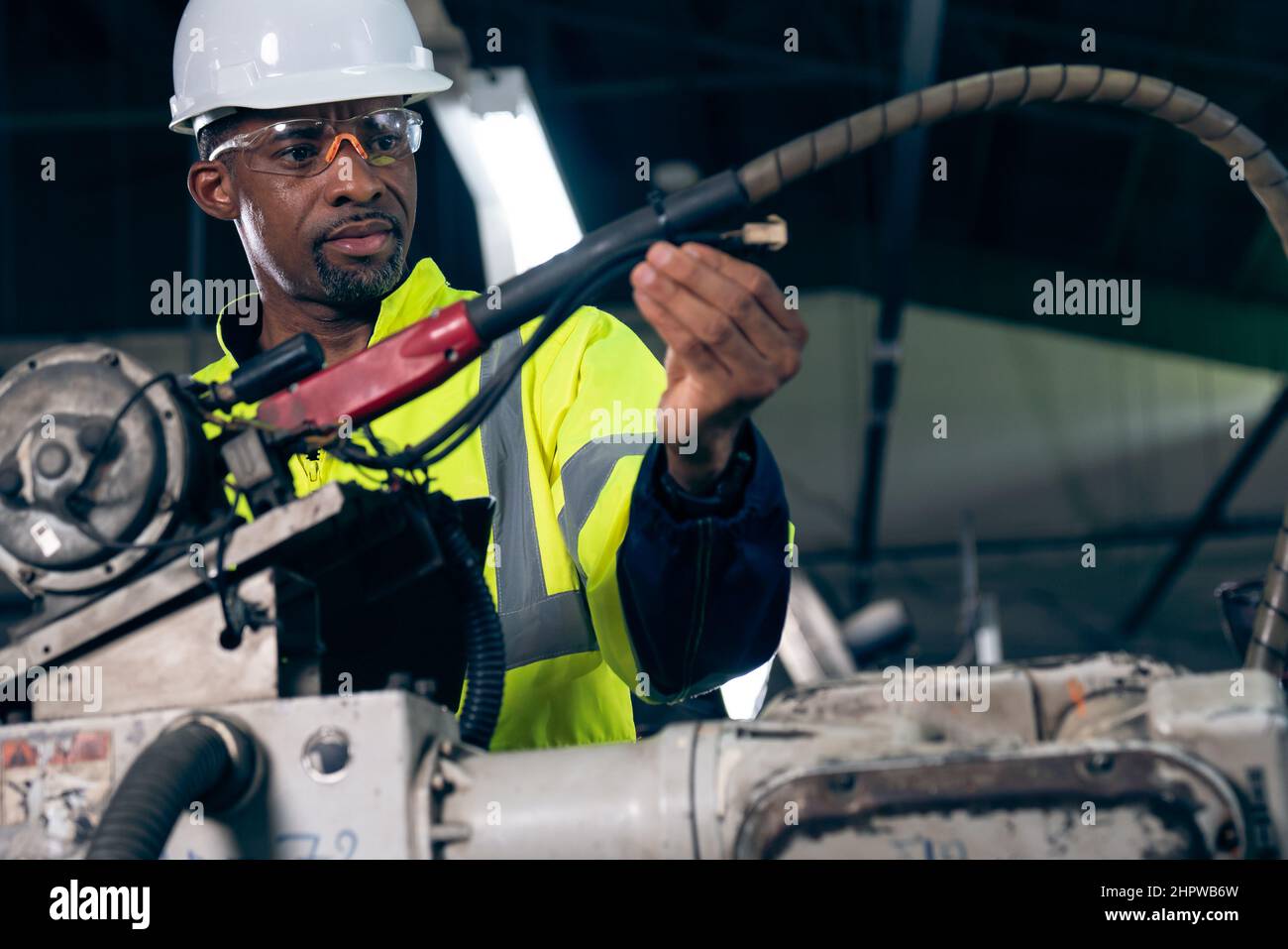 African American factory worker working with adept robotic arm in a ...