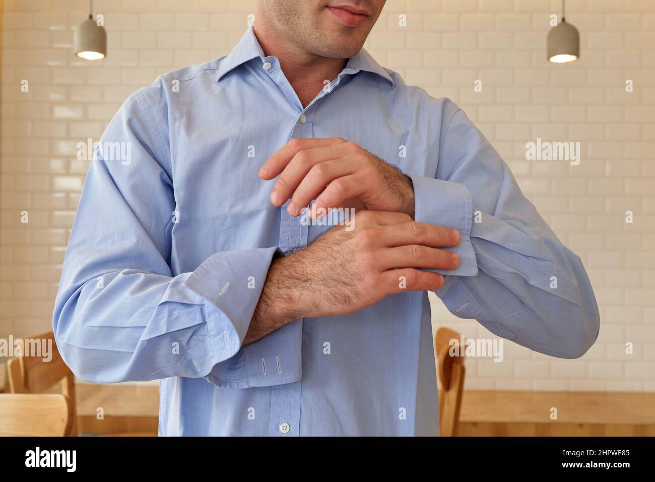 The man fastens the cufflink on the sleeve of his shirt. The groom ...