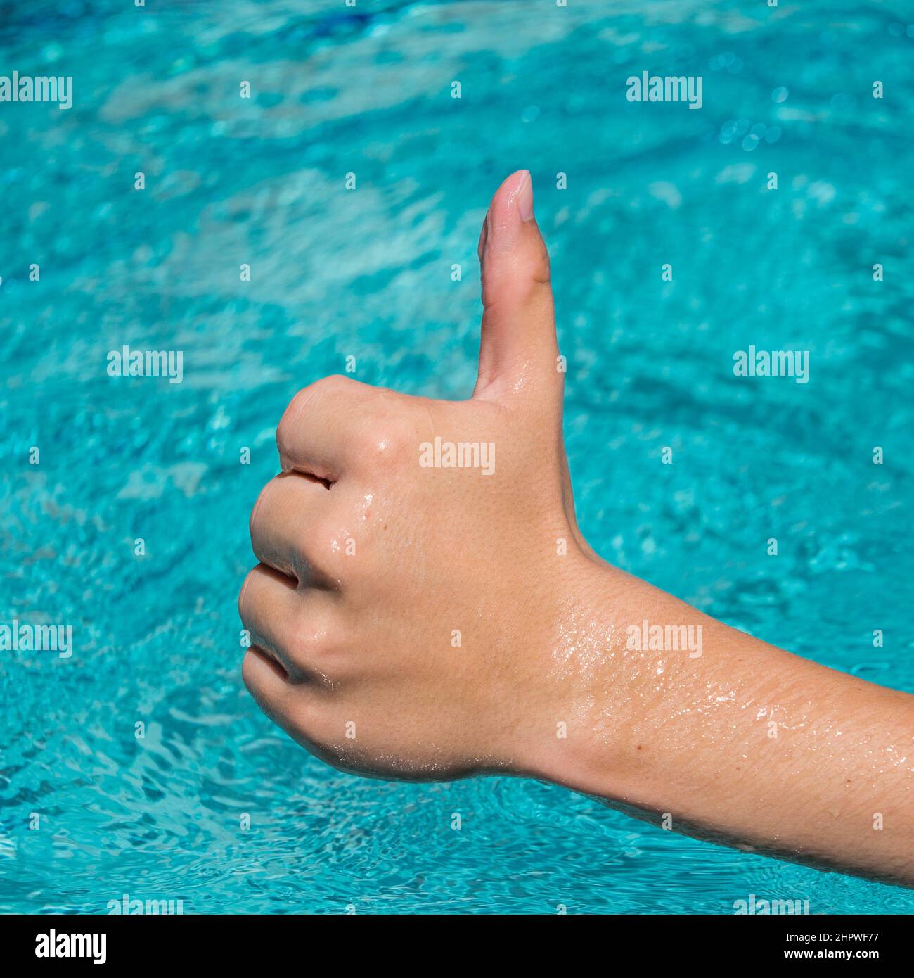 thumbs up sign of young man with wet hand, teenager with blue water as ...