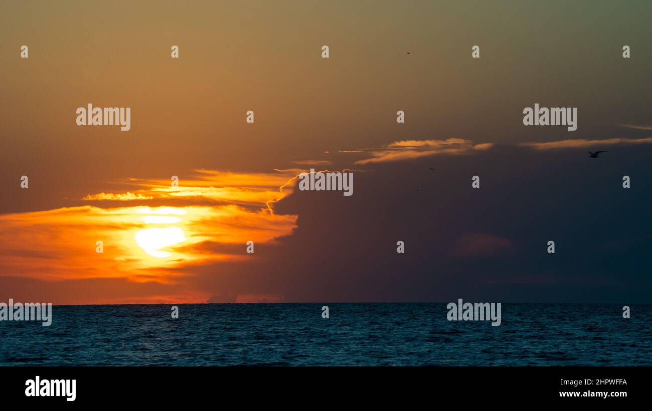 Epic colorful sunset illuminates clouds over blue waters Stock Photo ...