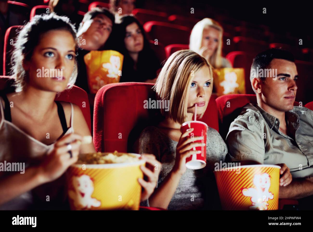 Sweet suspense. Friends sitting with refreshments and popcorn enjoying ...