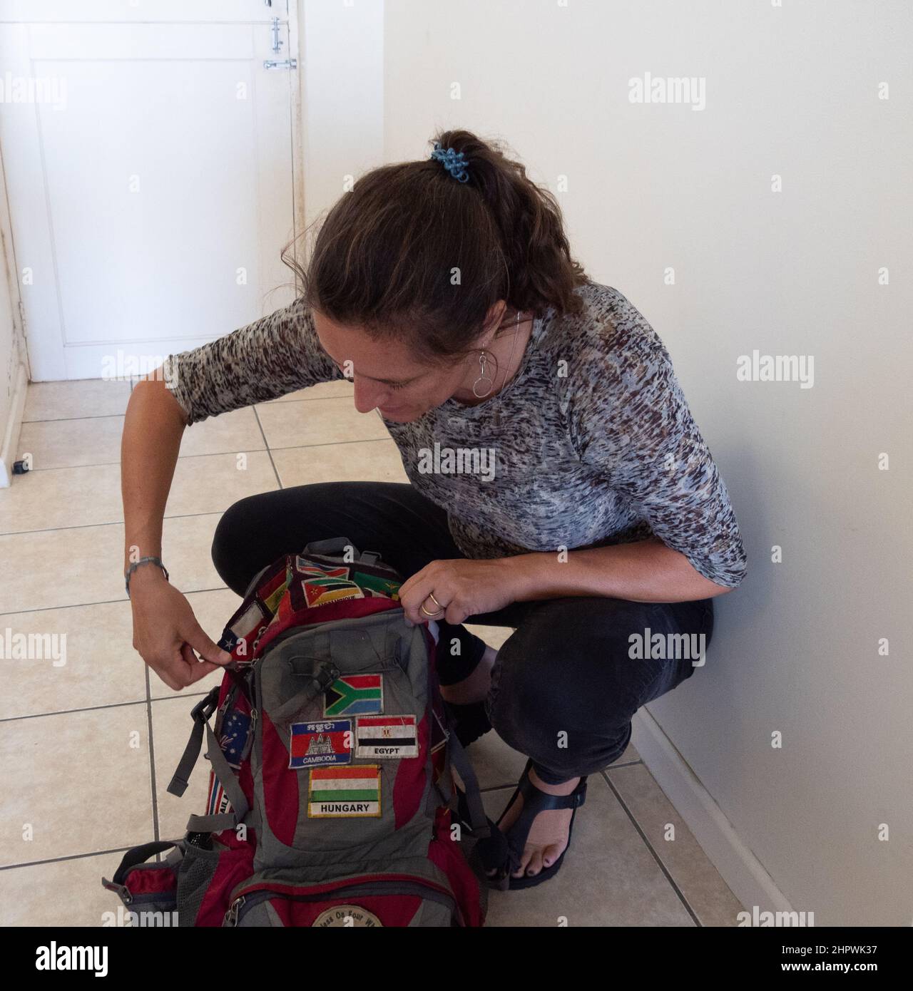 Woman getting ready to travel. She is packing her backpack which is ...