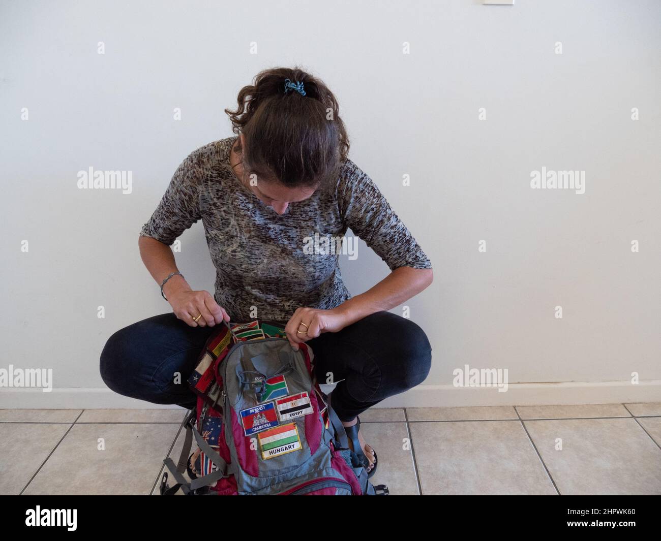 Woman getting ready to travel. She is packing her backpack which is ...