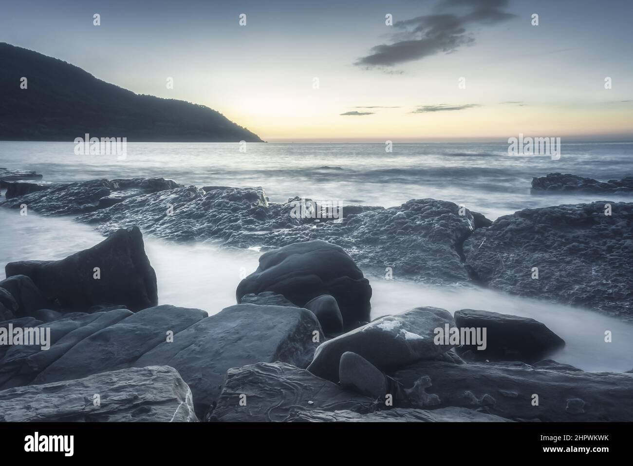 Sunset at the blue hour on the horizon and in the foreground a cliff to ...