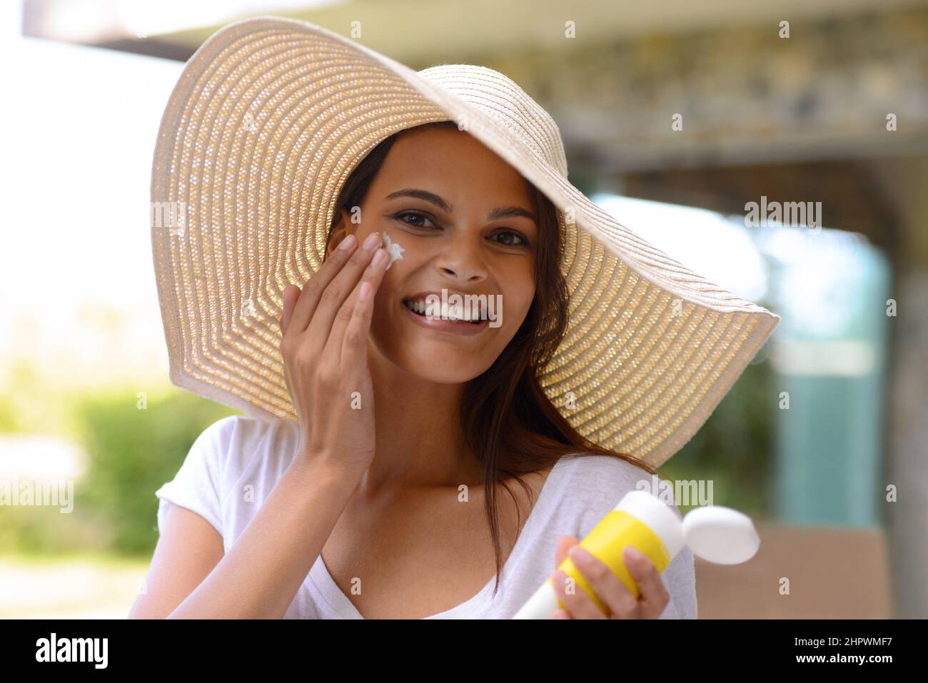 Better safe than sorry. An attractive young woman applying sunscreen to ...