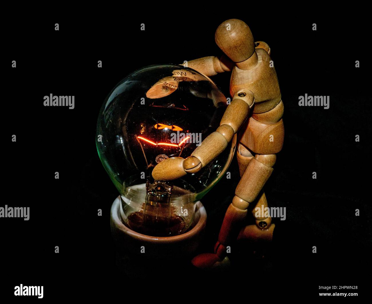 Still life, wooden figure with dimmed light bulb, symbol photo energy ...