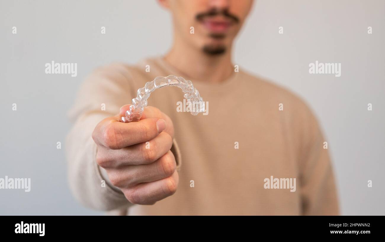 Caucasian young man showing an invisible silicone aligner for dental ...