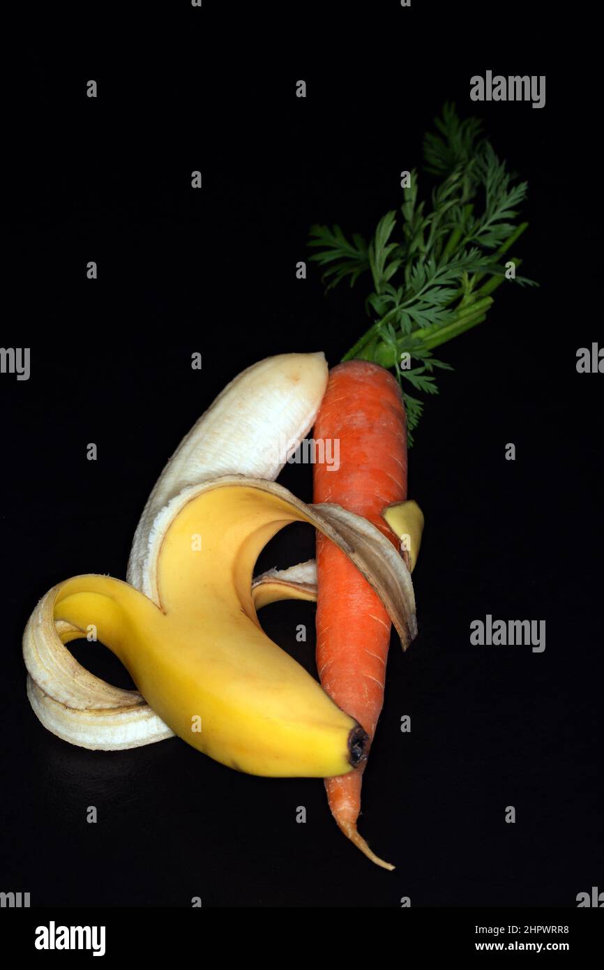 A banana hugs a carrot, symbol photo for love and friendship, studio ...