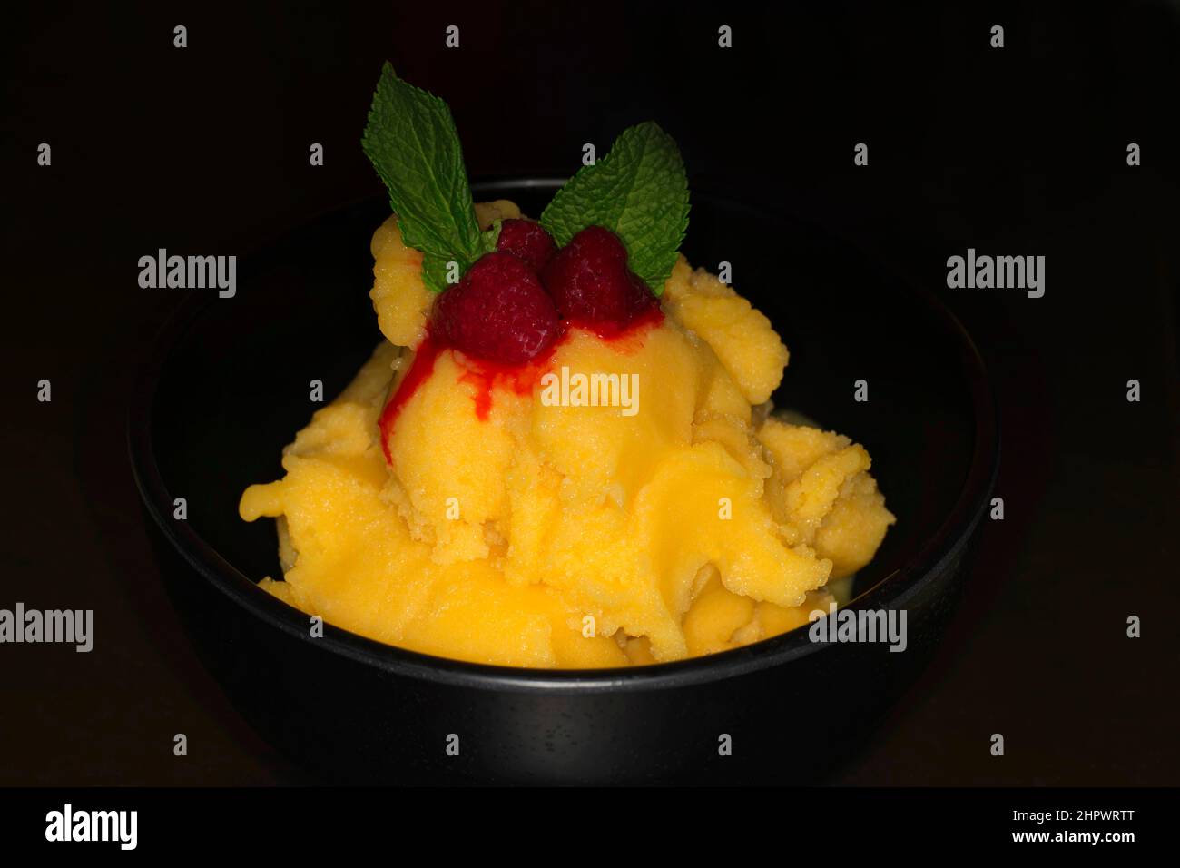 Mango sorbet with raspberries and fresh mint, studio photography with ...