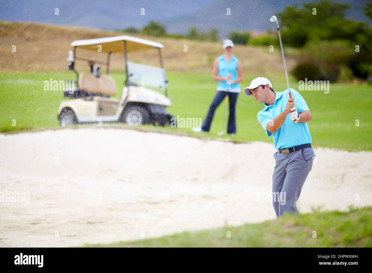 In and quickly out of a bunker. A young male golfer chipping his ball ...