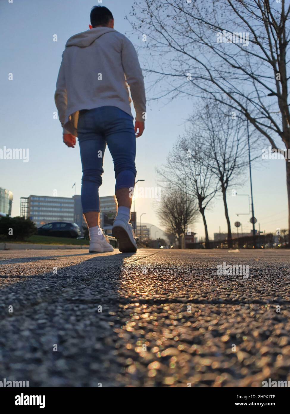Vertical shot of a young male walking on the street at sunset Stock ...