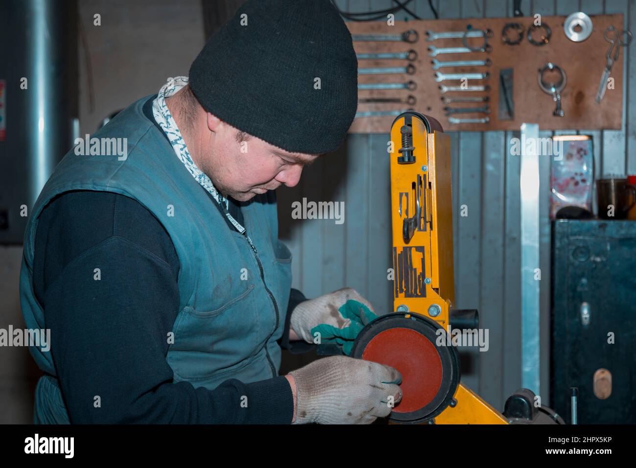 A worker using a belt sander processes a metal part Stock Photo - Alamy