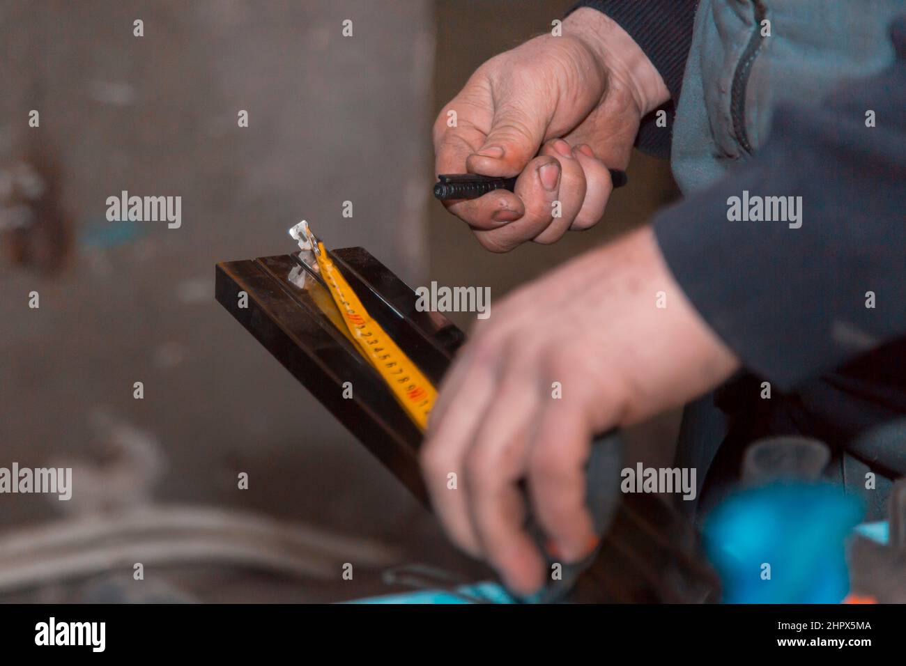 A worker marks a stainless steel profile pipe with a marker using a ...