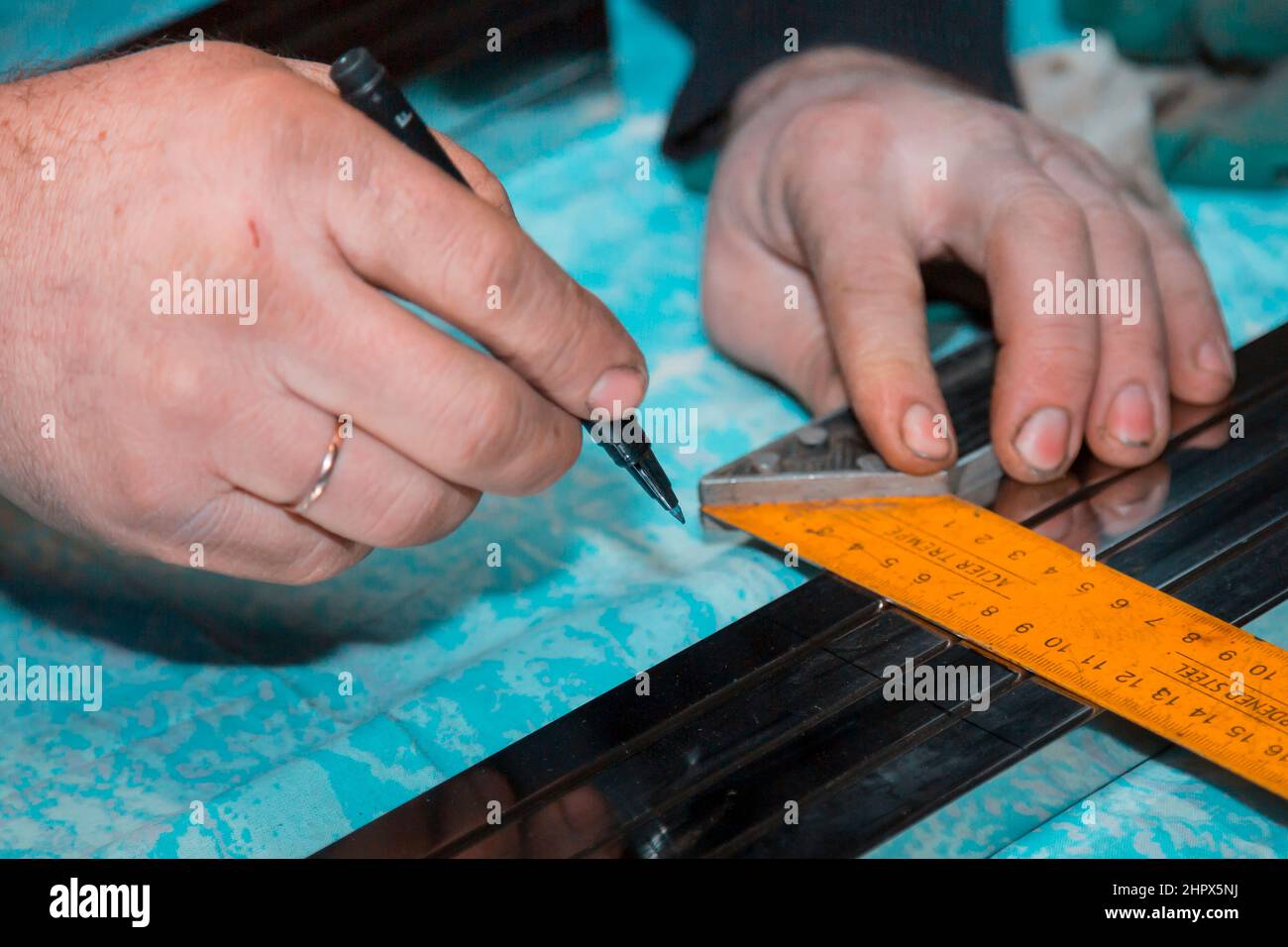 A worker marks a stainless steel profile pipe with a marker using a ...