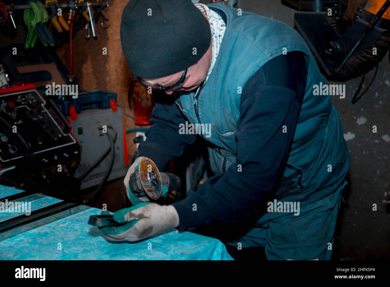 A worker using a grinder processes a metal part Stock Photo - Alamy