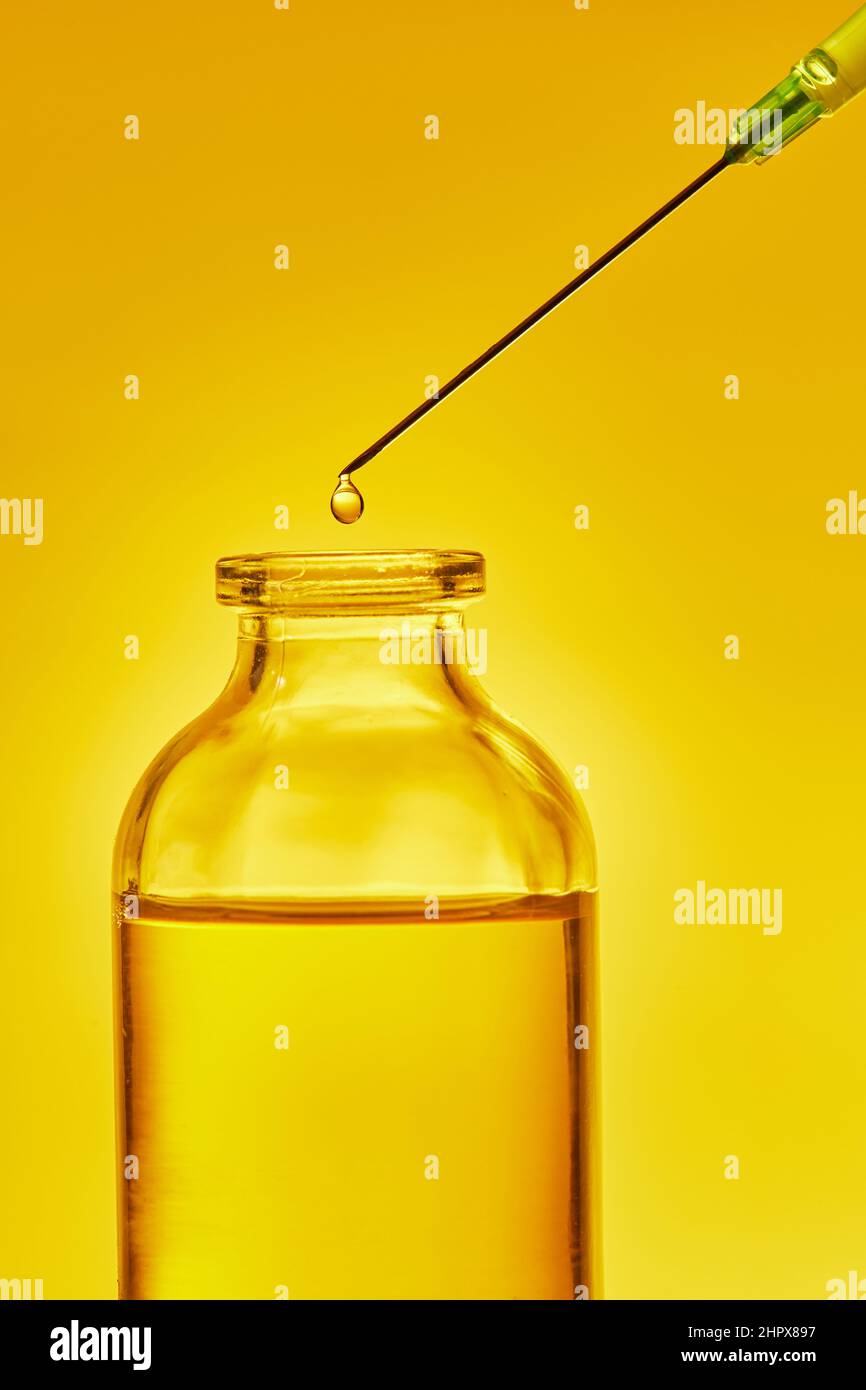 A drop of liquid drips from the needle of a medical syringe into the ...