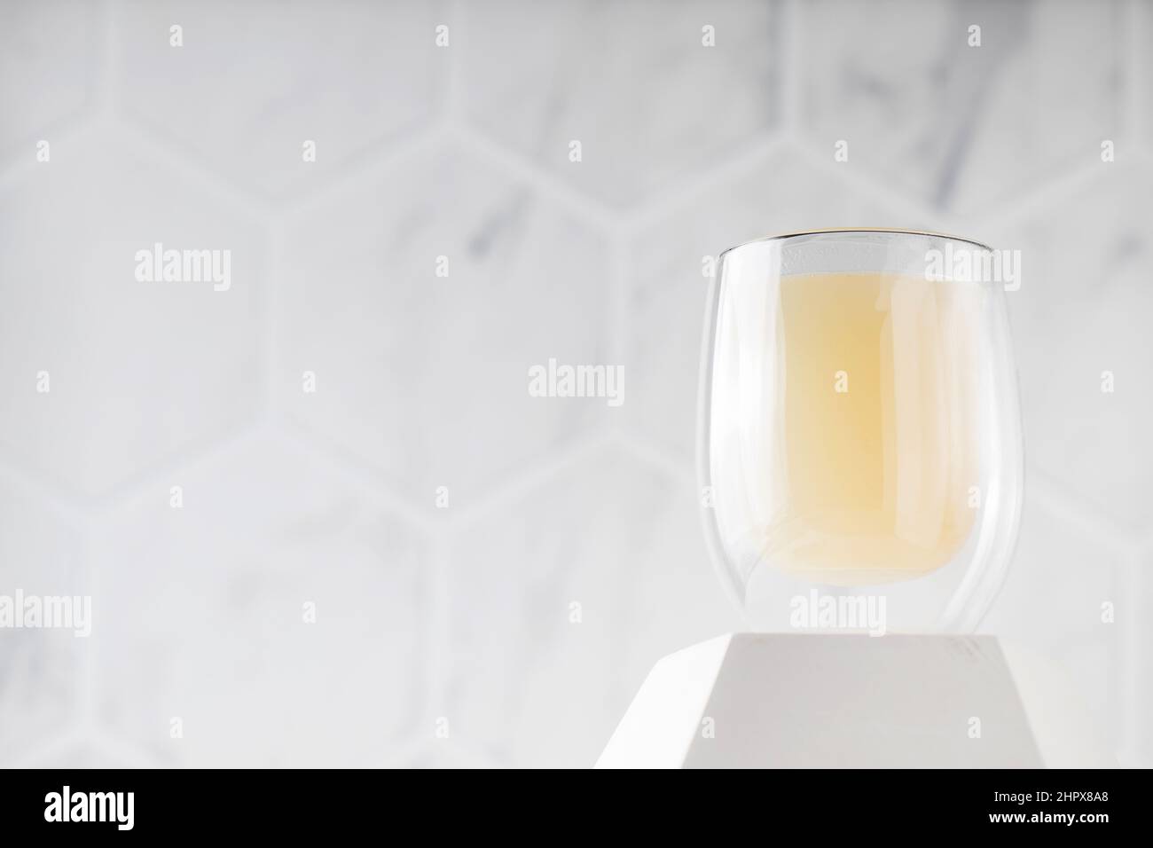 Healthy bone broth in a transparent mug on a pedestal on a light ...