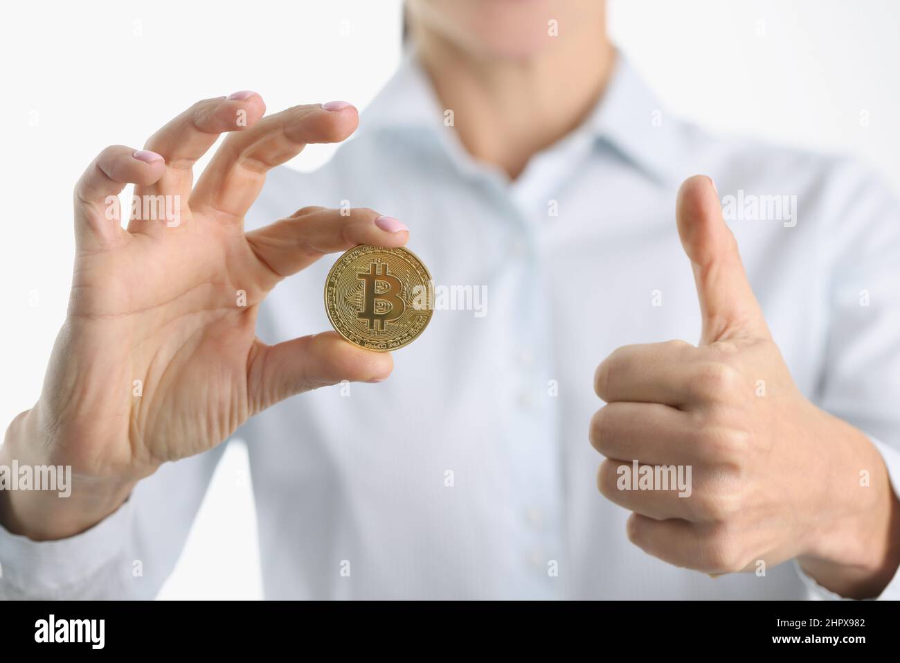 In female hands, a bitcoin coin gesture thumbs up Stock Photo - Alamy