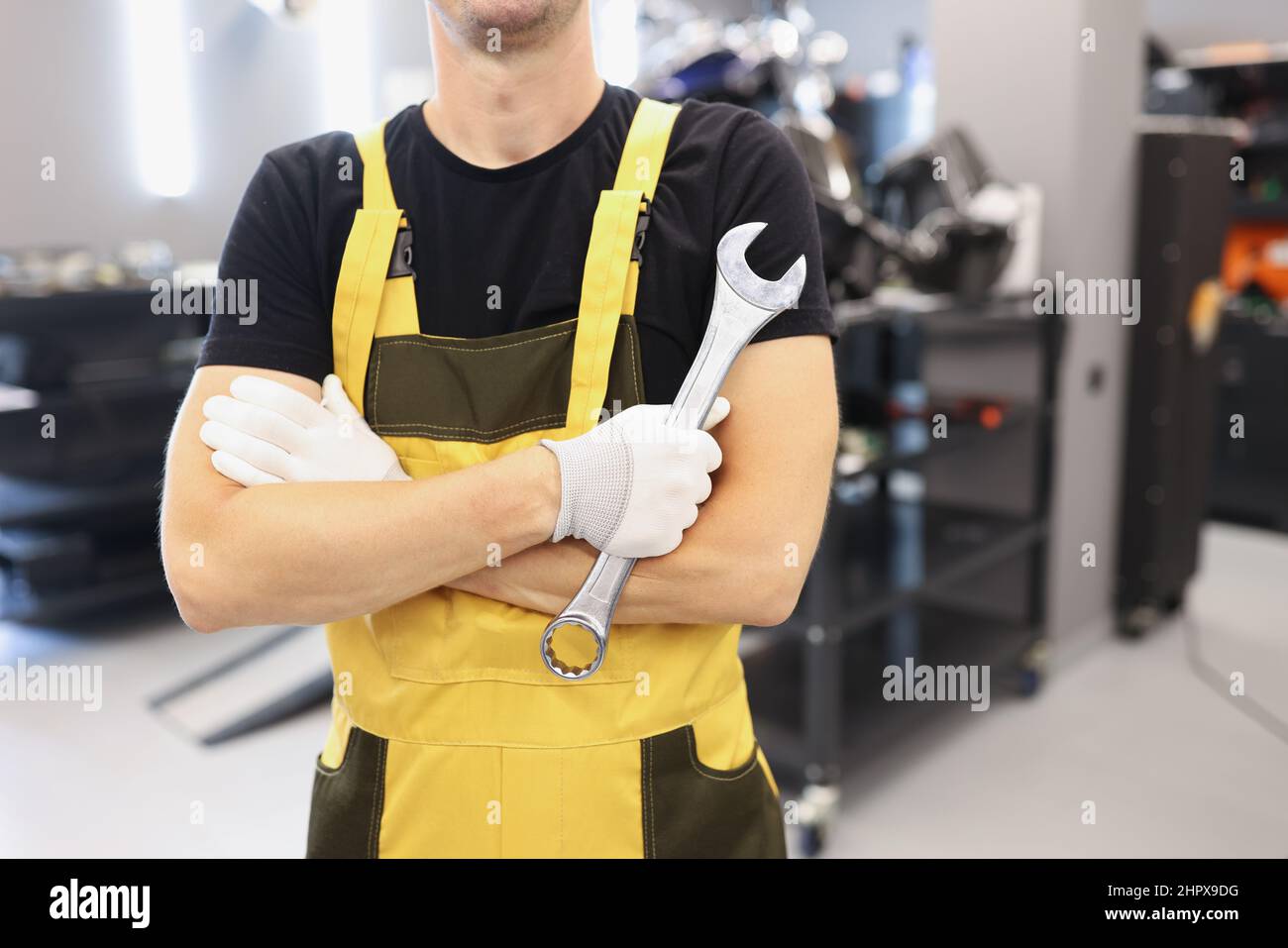 Strong man in yellow overalls holding a wrench Stock Photo - Alamy