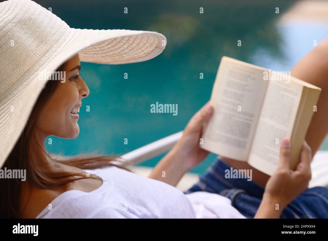 Woman reading book by pool hi-res stock photography and images - Alamy