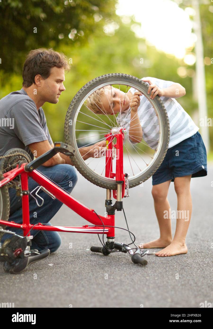 Learning from the best. Young father and son fixing a bicycle tyre ...