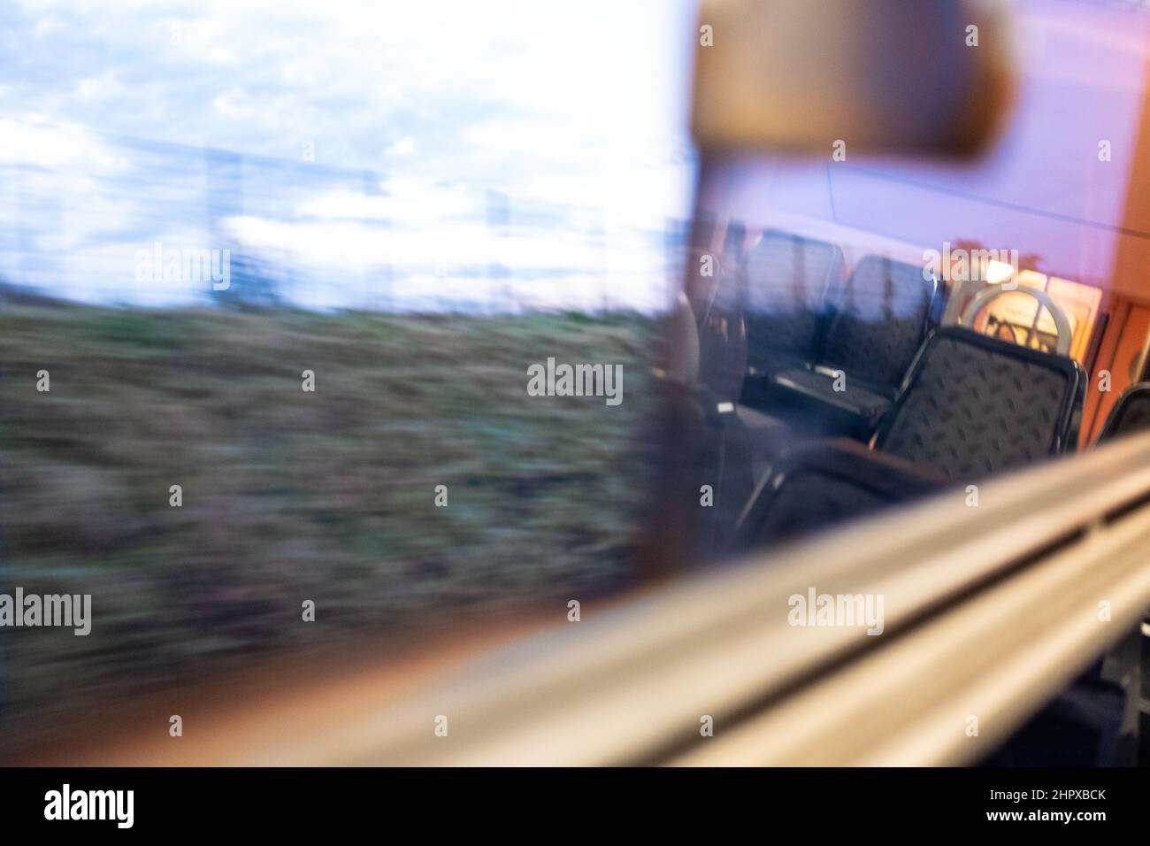 Movement blur landscape seen from a train window with seats reflected ...