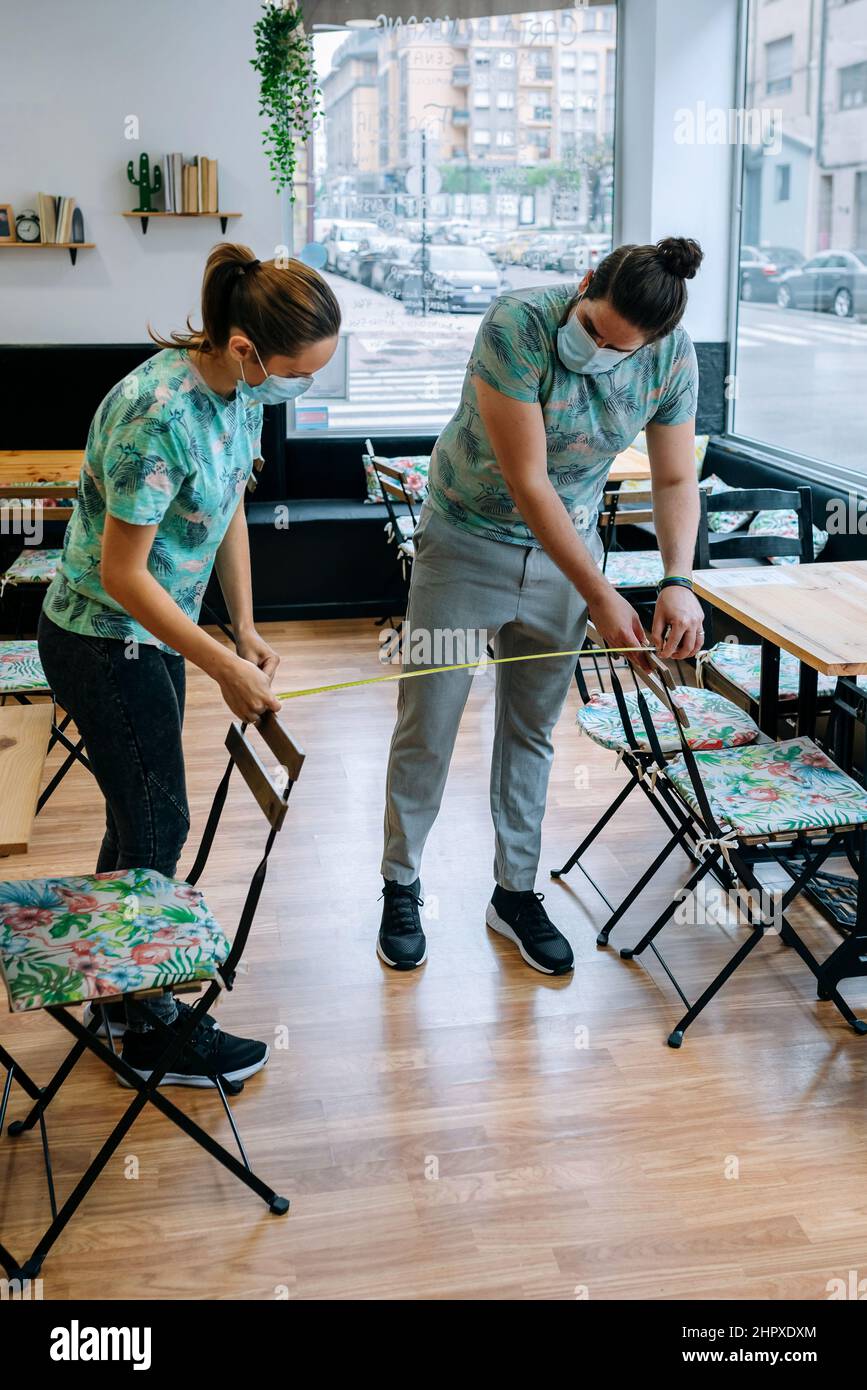 Workers measuring social distance between chairs Stock Photo - Alamy