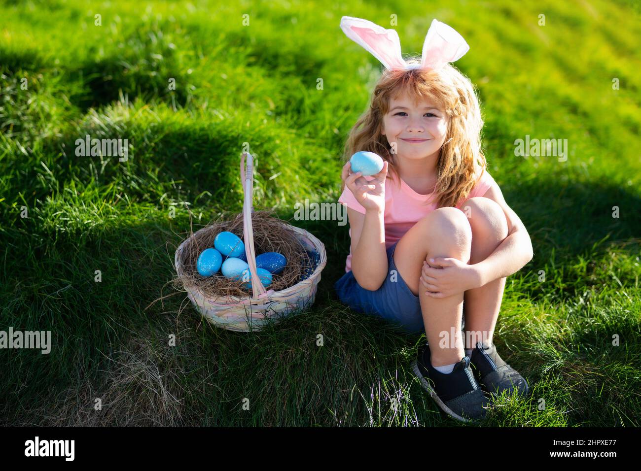 Happy Easter for children. Boy in bunny ears with colorful eggs play ...