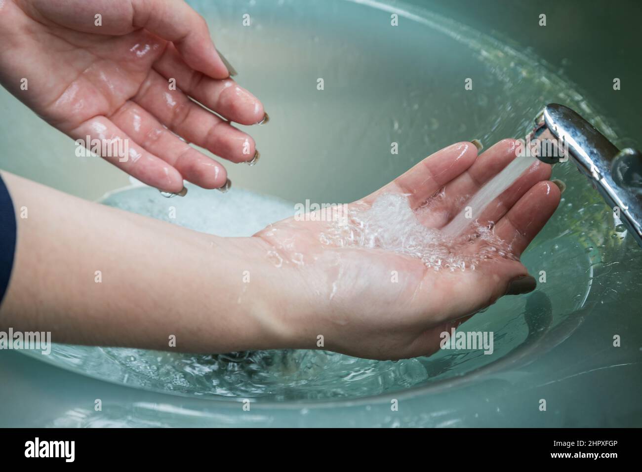 Washing hands under flowing tap water flow on sink Stock Photo - Alamy