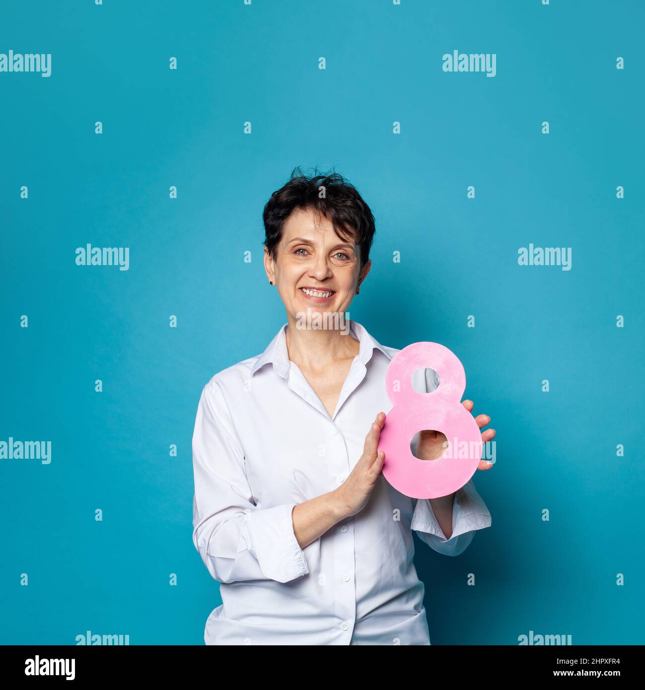 Happy smiling mature woman brunette with short hair holding pink eight ...