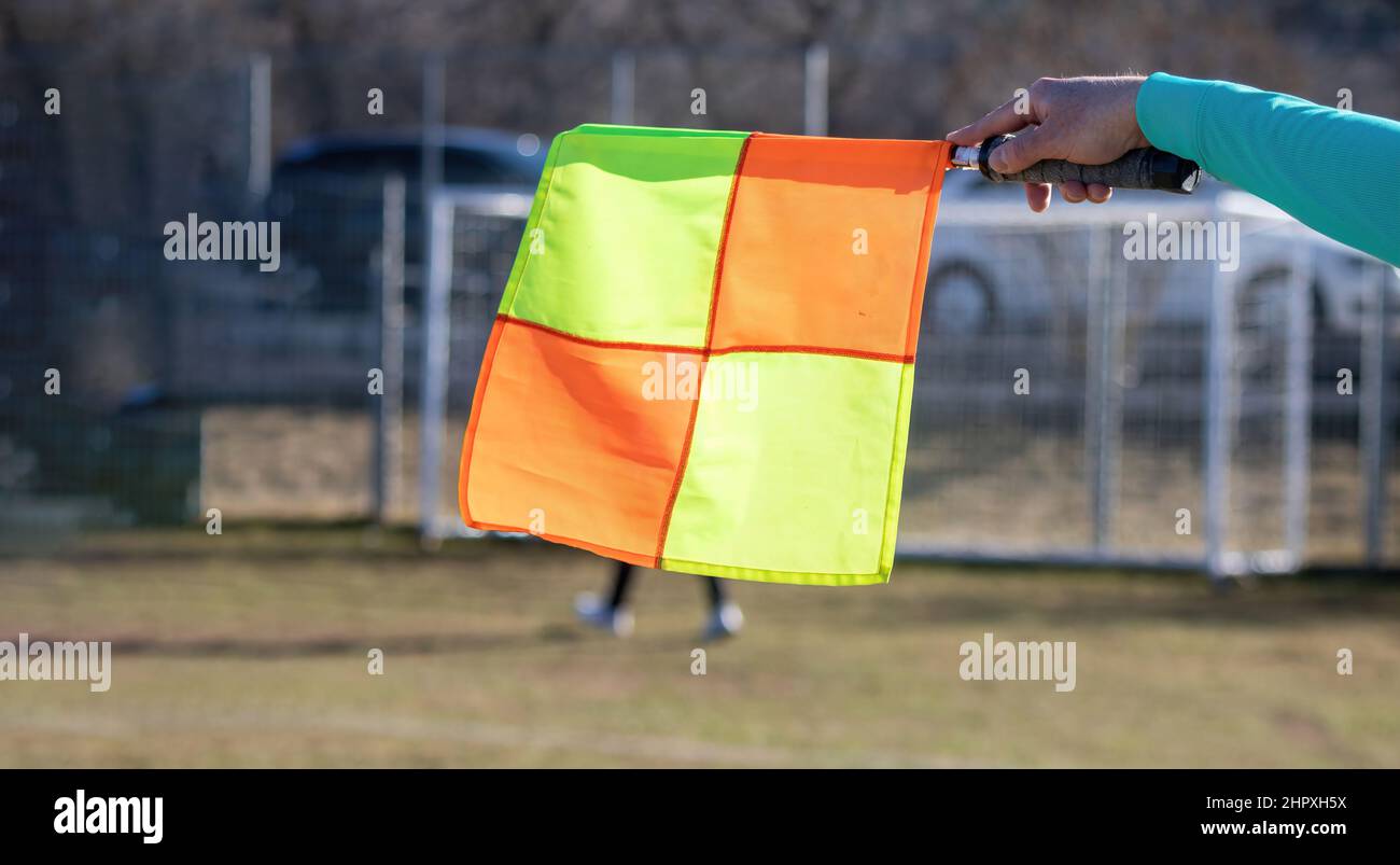 Football soccer arbiter assistant with flag at hands. Blurred green ...