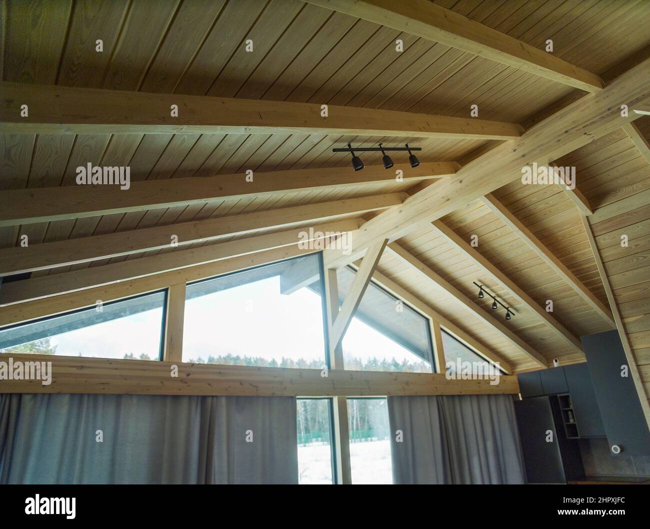 triangle wooden ceiling and a wide window with curtains, indoor wide ...