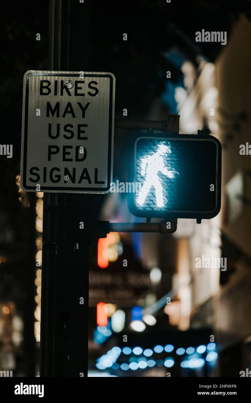 Traffic sign and a poster saying bikes may use ped signal at night ...