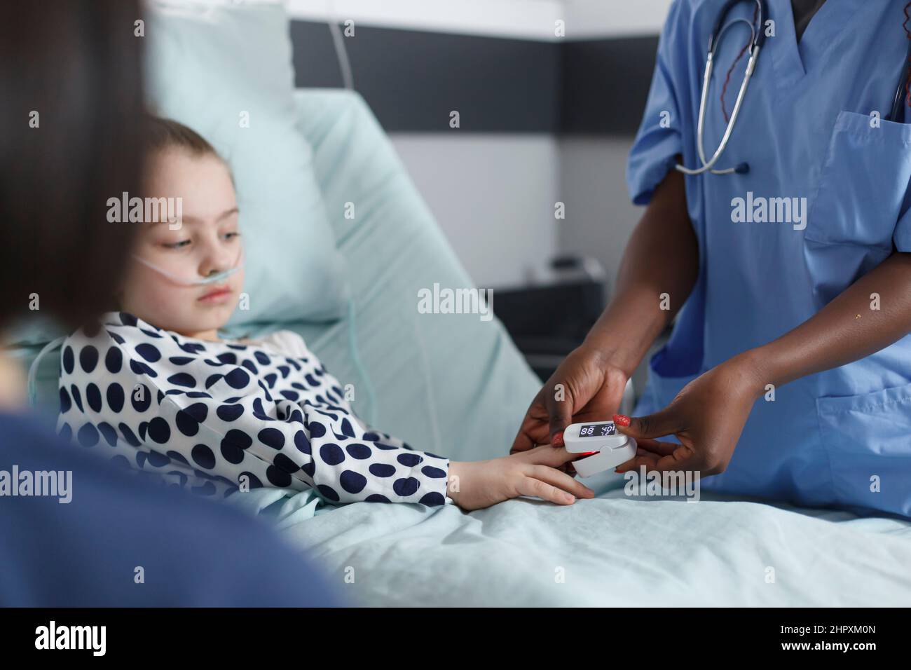 Pediatric clinic nurse measuring sick little girl oxygen levels using ...