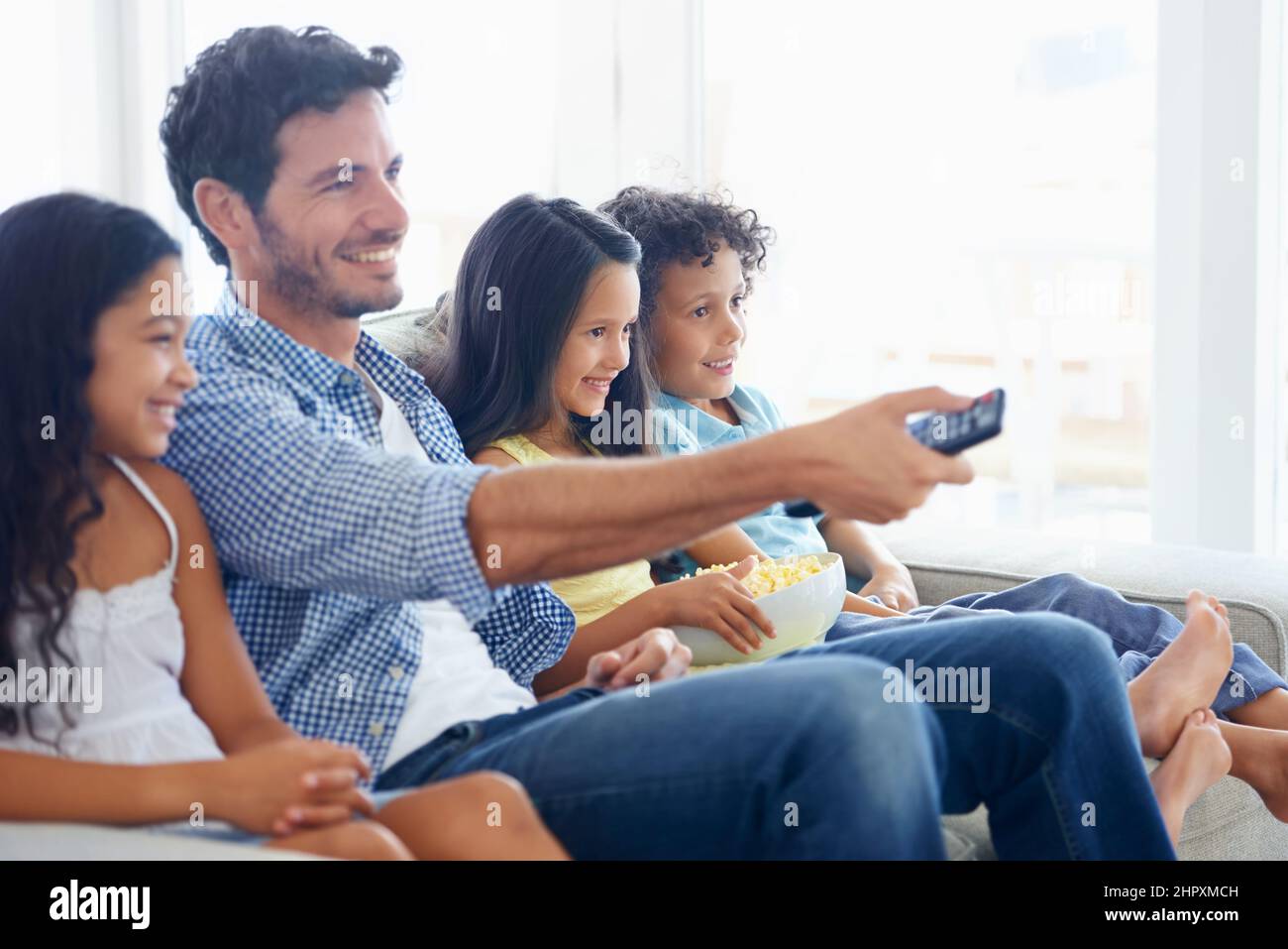 We love comedies. Shot of a family eating popcorn while sitting on a ...