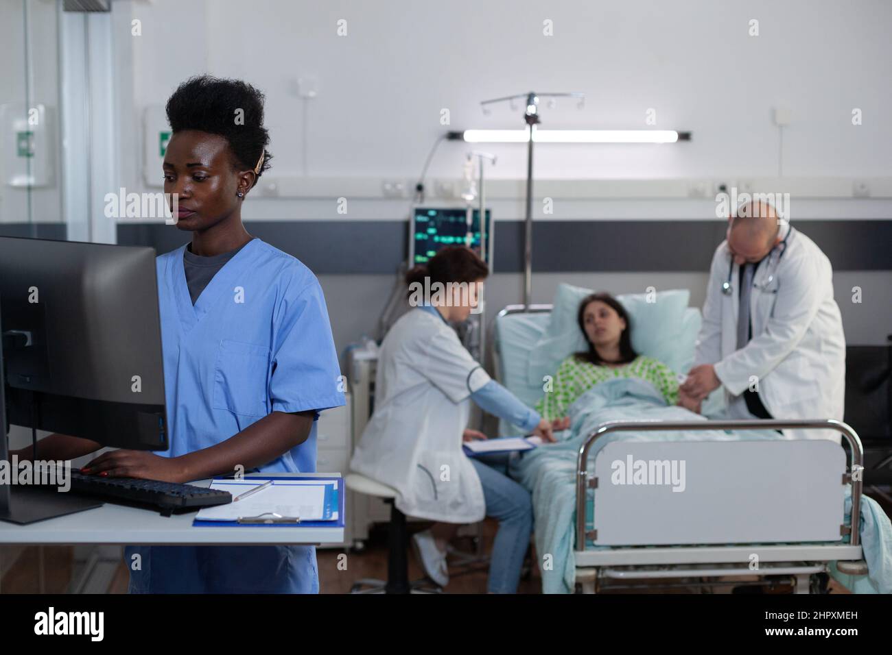 Nurse using computer to read patient medical history and lab results in ...