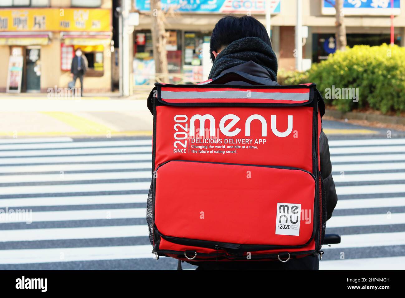 TOKYO, JAPAN - February 22nd, 2022: Menu delivery rider at a crosswalk ...