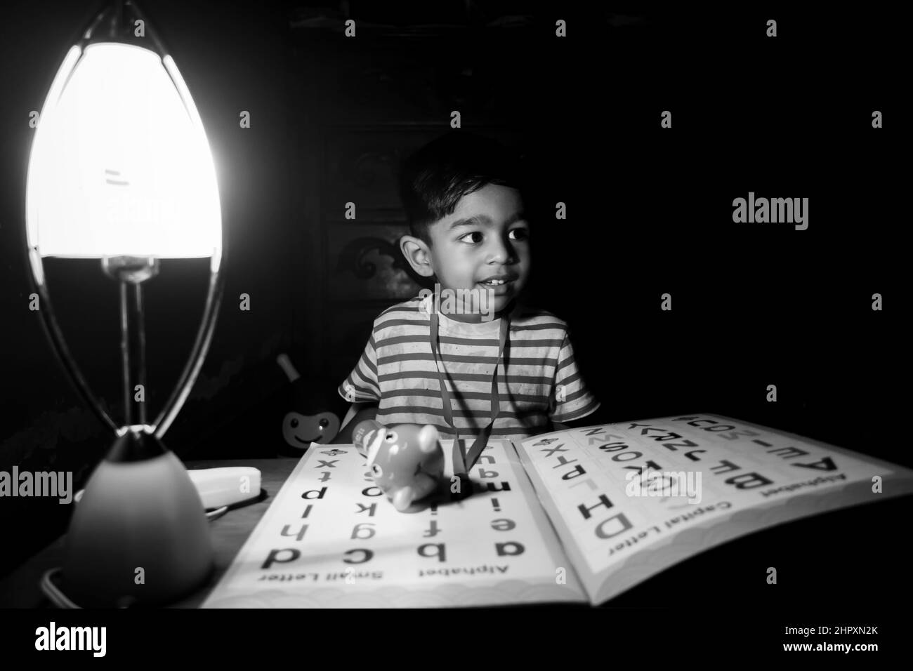 A boy learning the English alphabet using a charger lamp In the evening ...
